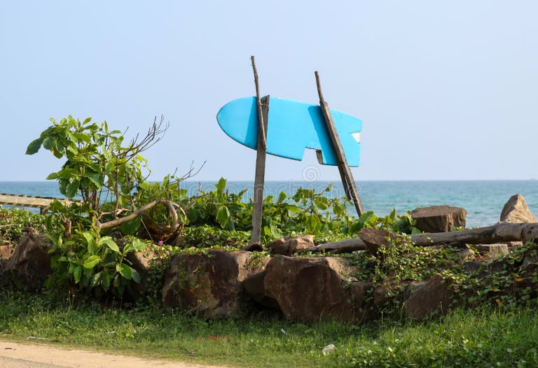 A Blue Surfboard is Leaning Against a Rock on a Beach Stock Image ...