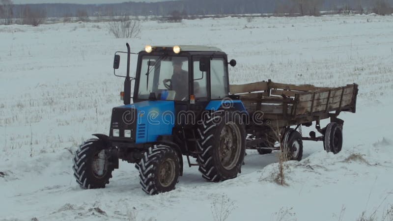 Blue Tractor with Trailer Rides on Snow Field Stock Video - Video of ...