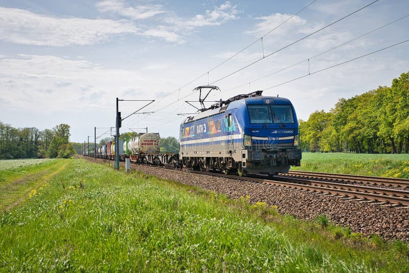 Blue Train Chugging Down a Set of Tracks in a Rural Landscape ...