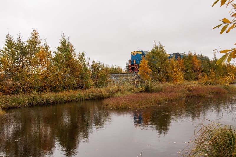 Blue Train are Going through Yellow Forest Near the River. Autumn Trees ...