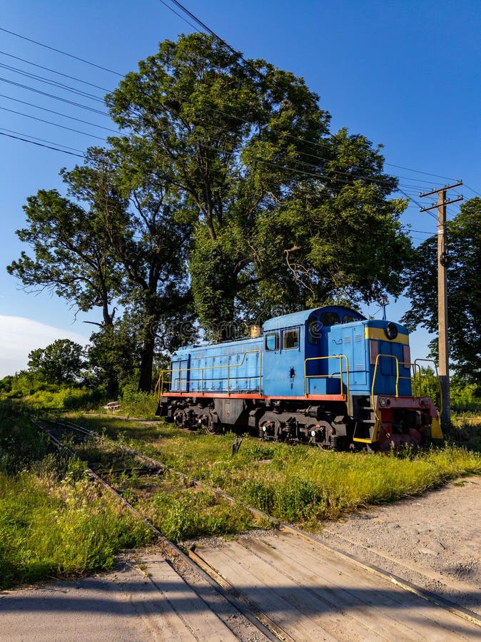 A Blue Train Traveling Down Train Tracks Next To a Forest Editorial ...