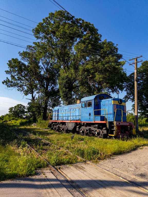 A Blue Train Traveling Down Train Tracks Next To a Forest Editorial ...