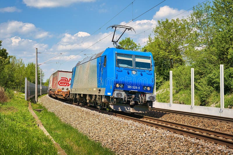 A Blue Train Traveling Down Train Tracks in Front of Trees Editorial ...
