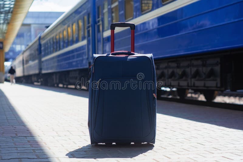 Blue Travel Suitcase on Train Station Platform with a Blue Train in the ...