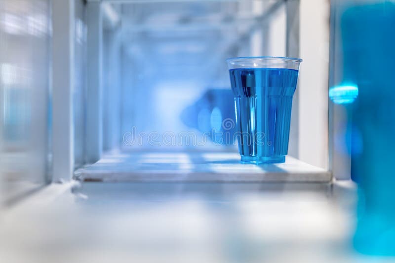 Blue Water Inside Clear Plastic Cup on White Metal Shelf Structure for ...