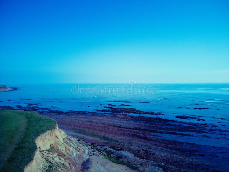 Blue Water Ocean Beach Muddy Cliffside Stock Photo - Image of clouds ...