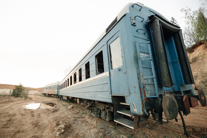 A Blue, Destroyed Train Stands on Rails with Broken Windows in the ...
