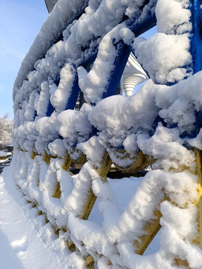 A Blue and Yellow Fence Covered in Snow Next To a Building Stock Photo ...