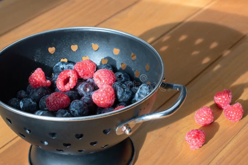 Blueberries and Raspberries in Colander on Wooden Rustick Table with ...