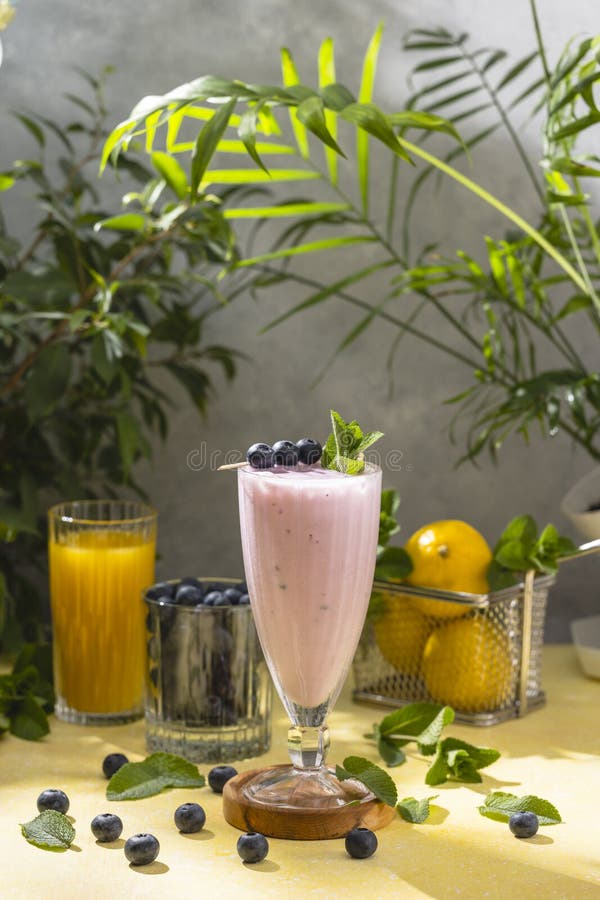 Blueberry Milkshake Standing on Yellow Counter with Mint and Lemons ...
