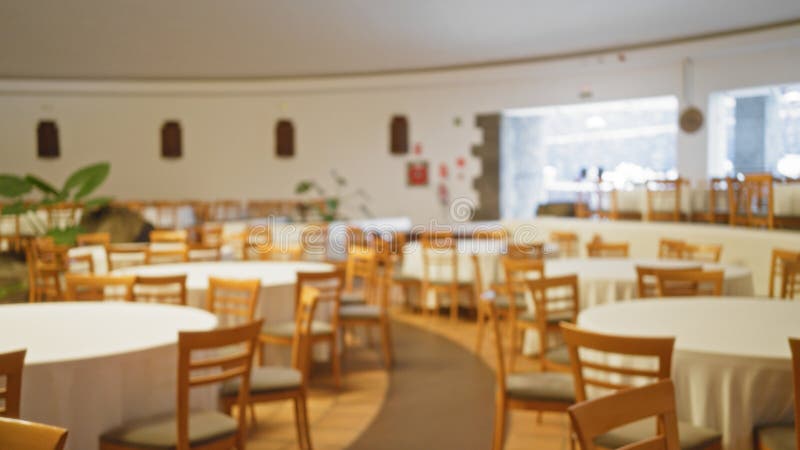Blurred Empty Wedding Hall with Round Tables and Wooden Chairs Set for ... Blurred Empty Wedding Hall with Round Tables and Wooden Chairs Set for ...