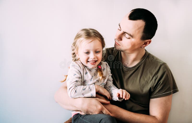 Blurred Young Dad Plays With His Daughter In His Arms In The Room On