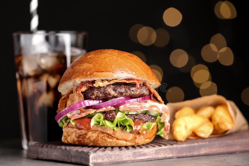 Board with Burger and Cola Against Blurred Lights Stock Image - Image ...