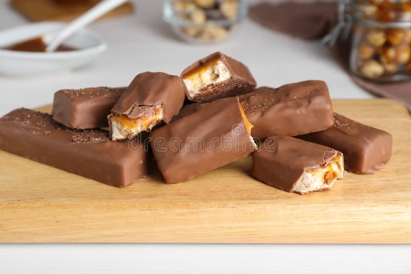Board with Delicious Chocolate Bars and Nuts on White Wooden Table ...