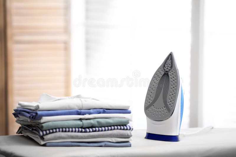 Iron and a Stack of Colored Clothes on a White Background. Ironing of ...