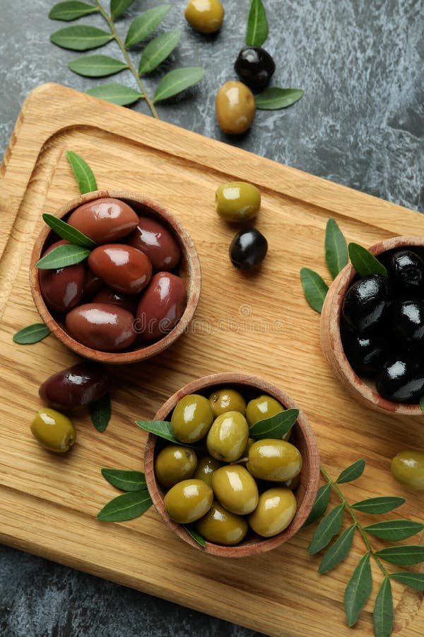 Board with Olives and Leaves on Black Smokey Background Stock Photo ...