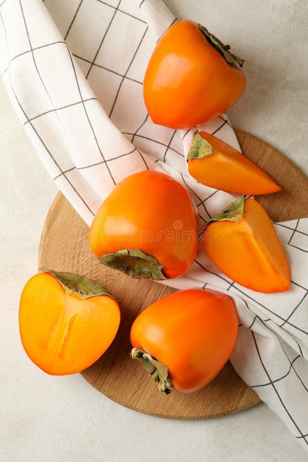 Board with Persimmon and Kitchen Towel on White Table Stock Image ...