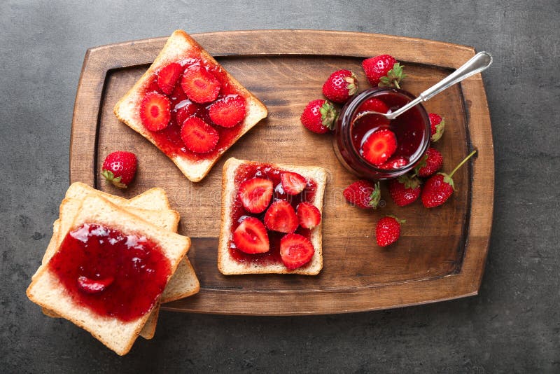 Board with Slices of Bread and Delicious Strawberry Jam on Dark Table ...