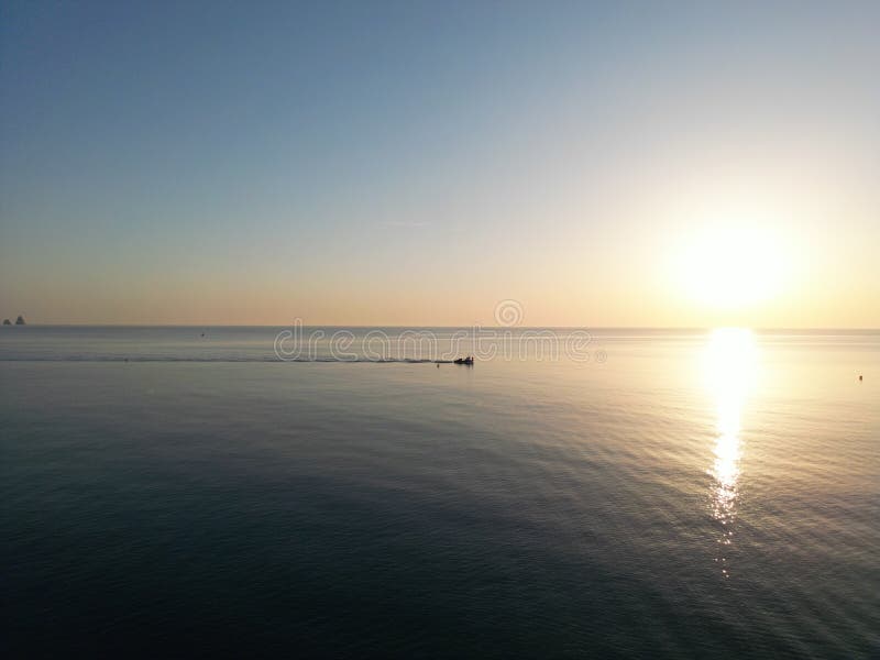 A Boat Sailing on the Water and Heading Towards the Rising Sun Stock ...