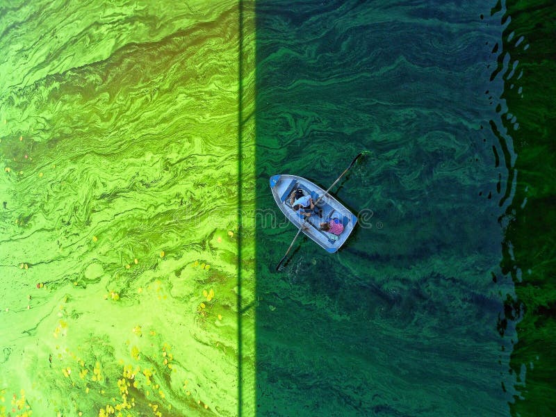 A Boat with Two Sailors Floats on Green Water Stock Photo - Image of ...