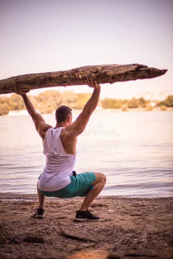 Bodybuilder on the Beach Picks Up a Tree. Stock Photo - Image of ...