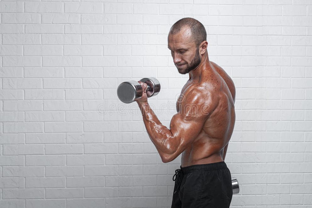 Bodybuilder Doing Exercises for Biceps with a Dumbbells Against Brick ...