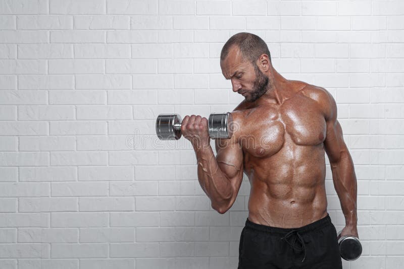 Bodybuilder Doing Exercises for Biceps with a Dumbbells Against Brick ...