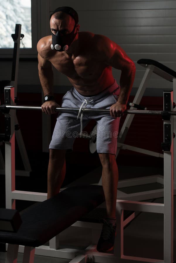 Man Exercising Push-Ups on Barbell in Elevation Mask Stock Photo ...