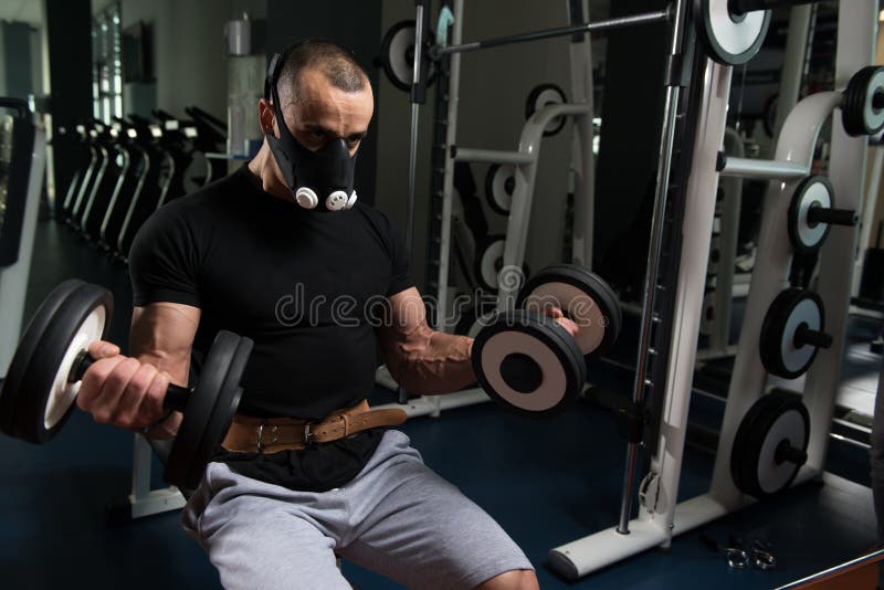Bodybuilder Exercising Biceps with Dumbbells in Elevation Mask Stock ...