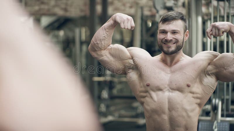A Bodybuilder with a Tattoo Makes a Pose with a Double Bicep in Front ...