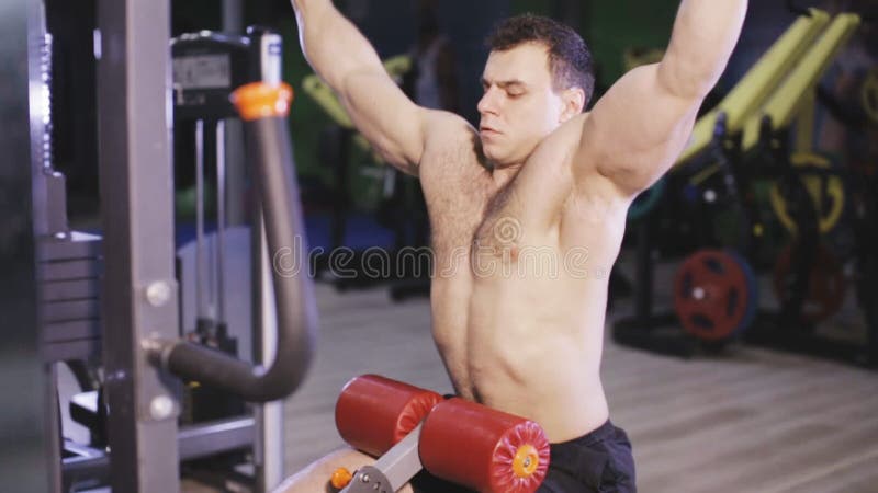 Young Man Bodybuilder is Working on His Back Muscles with Lat Machine ...