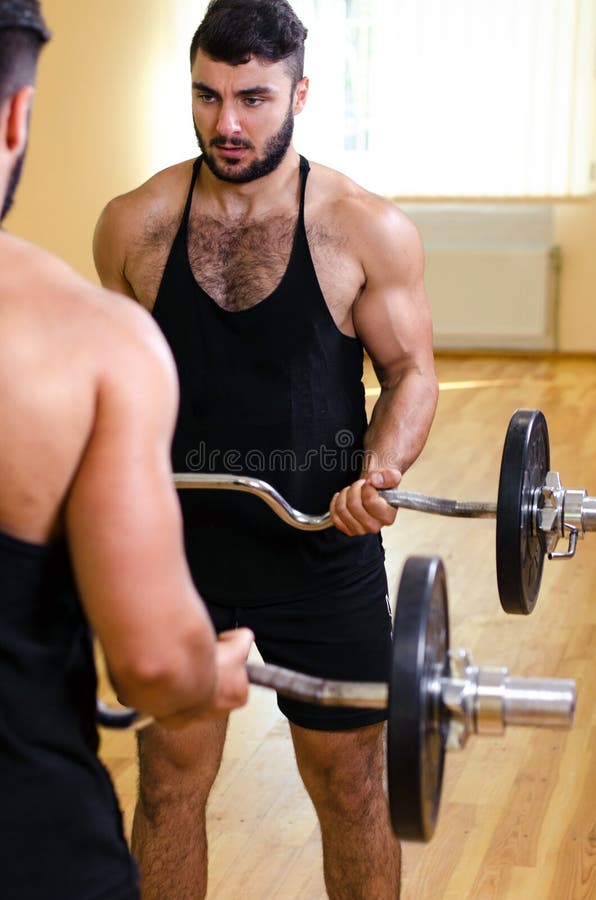 Young Man Standing Strong in Front of a Mirror and Flexing Muscles ...