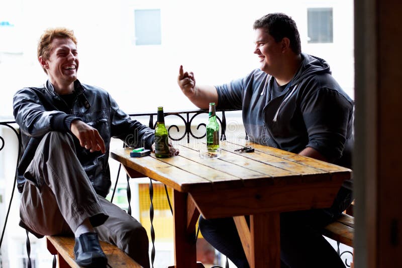 Bonding Over a Beer. Two Young Men Sitting at a Restaurant Drinking ...