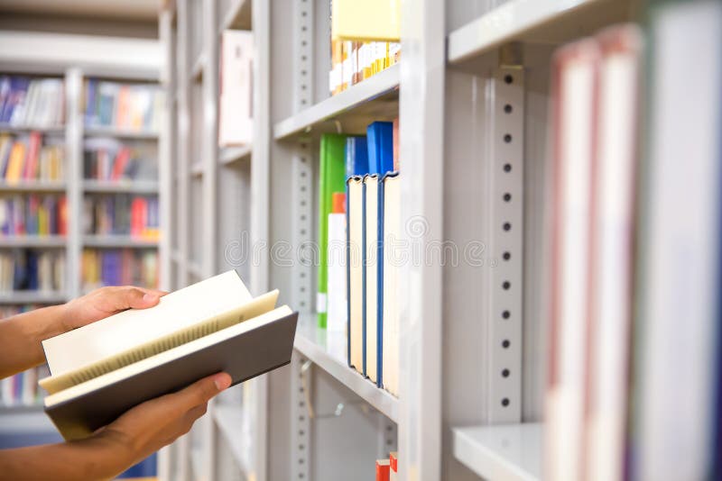 Close Up Hand Choosing and Open To Read a Book from Bookshelf in ...