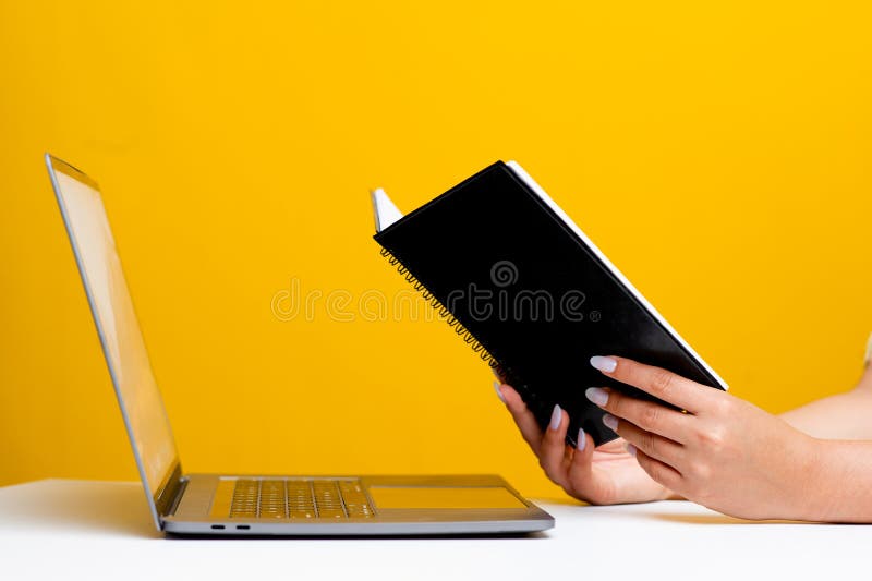 Hand and Book Side View Reading in a White Desk There is a Laptop in ...