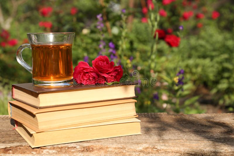 Book Stack with Glass Cup of Tea and Roses on Wooden Table in Garden ...
