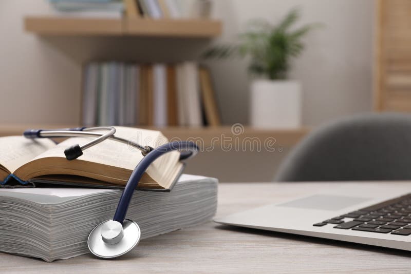 Book, Stethoscope, Laptop and Stack of Documents on Table Indoors ...