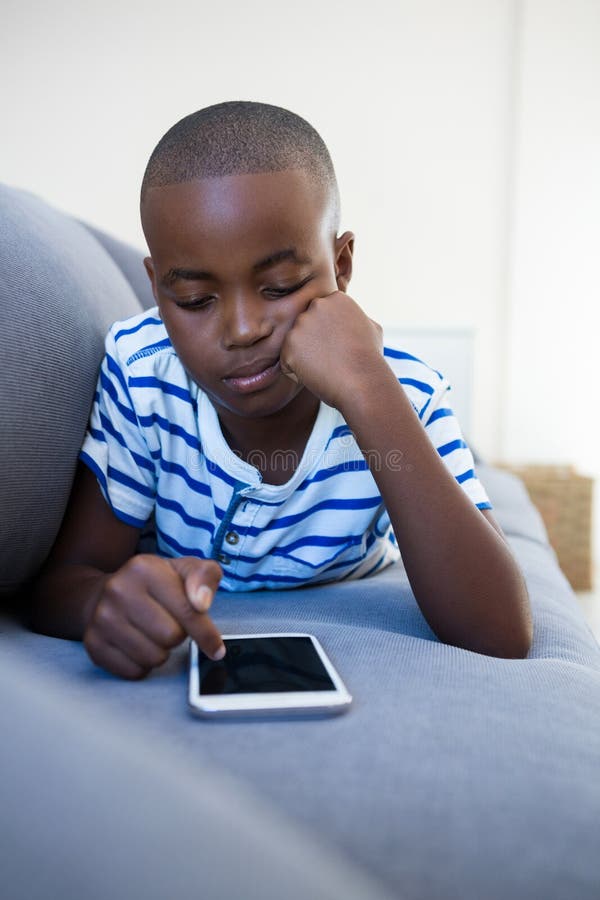 Bored Boy Using Mobile Phone while Lying on Sofa at Home Stock Image ...