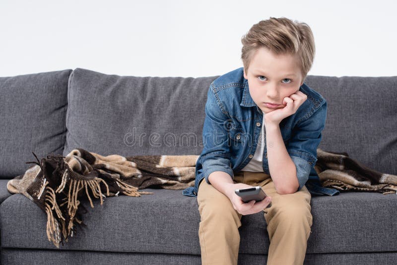 Bored Kid Boy Sitting on Sofa and Using Remote Control Stock Image ...