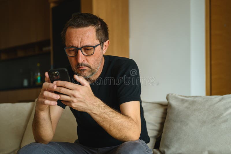 Bored Man Alone at Home Sitting on Sofa in Casual Clothes Holding ...