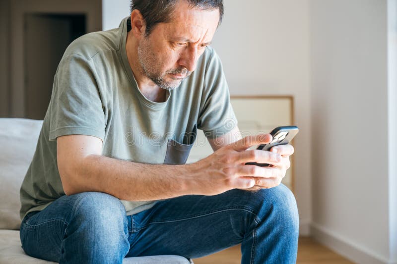Bored Man Alone at Home Sitting on Sofa in Casual Clothes Holding ...