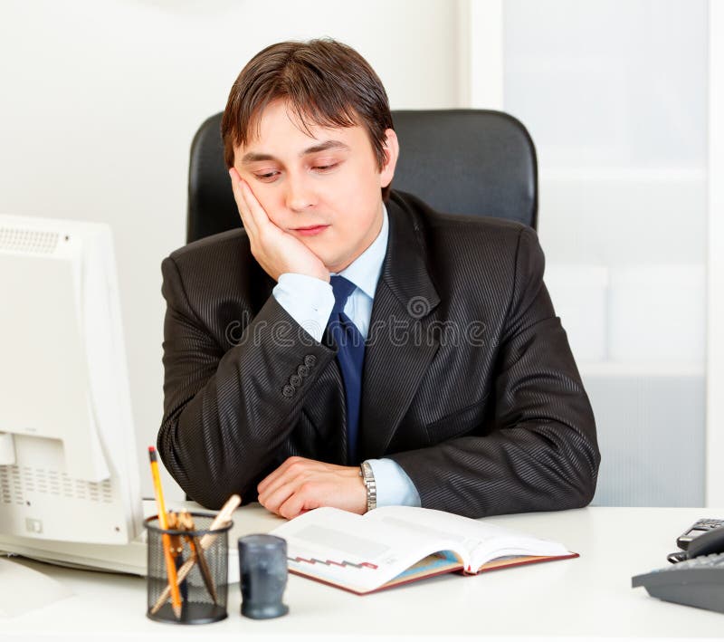 Bored Modern Businessman Sitting at Desk in Office Stock Image - Image ...