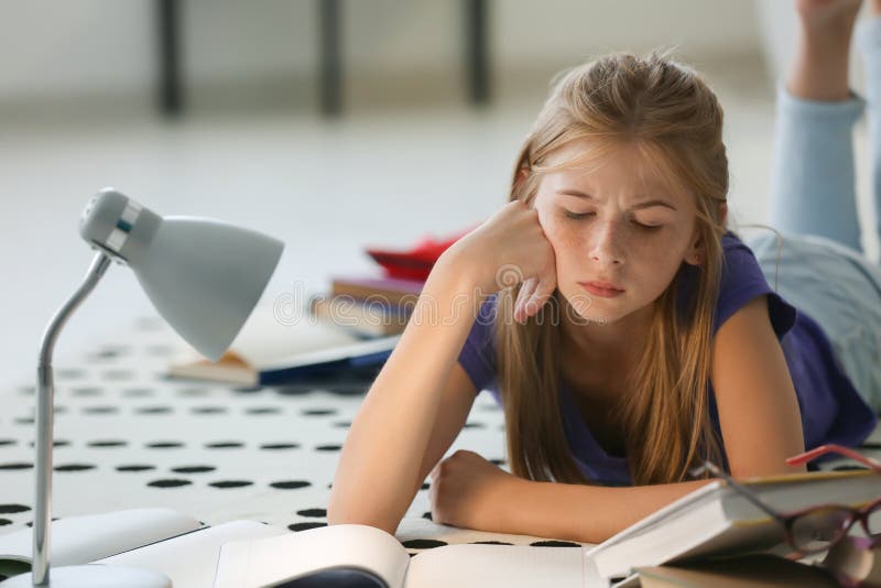 Bored Schoolgirl Doing Homework while Lying on Floor Indoors Stock ...