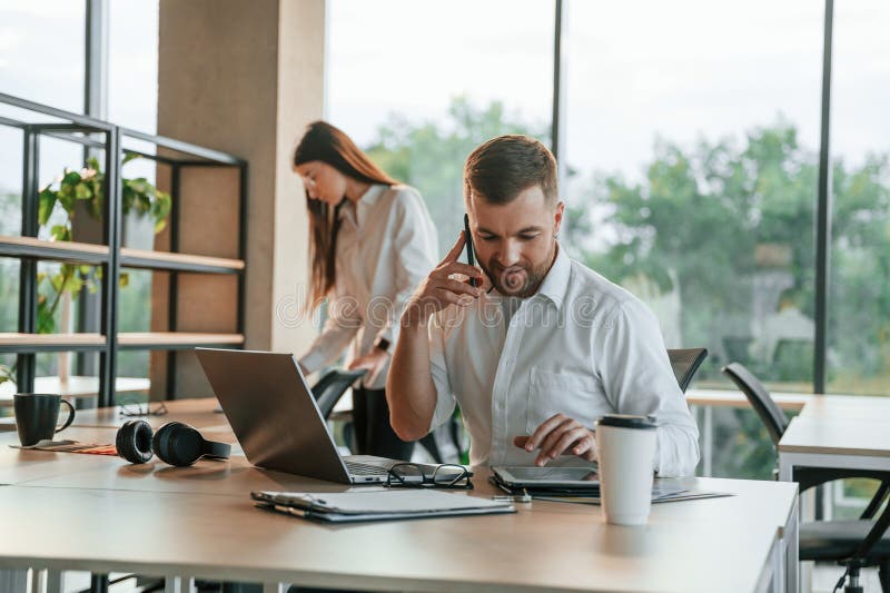 Boss is Having Conversation by the Phone. Man and Woman are Working in ...