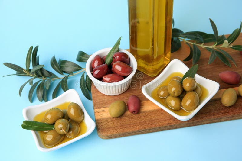 Bottle of Oil, Olives and Tree Twigs on Light Blue Background Stock ...