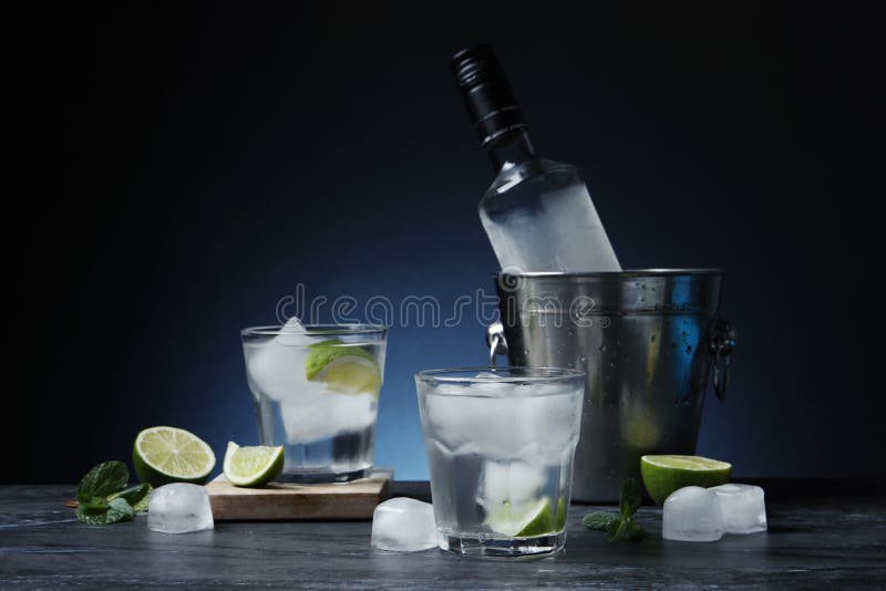 Bottle of Vodka, Glasses, Lime, Mint and Ice on Black Marble Table ...