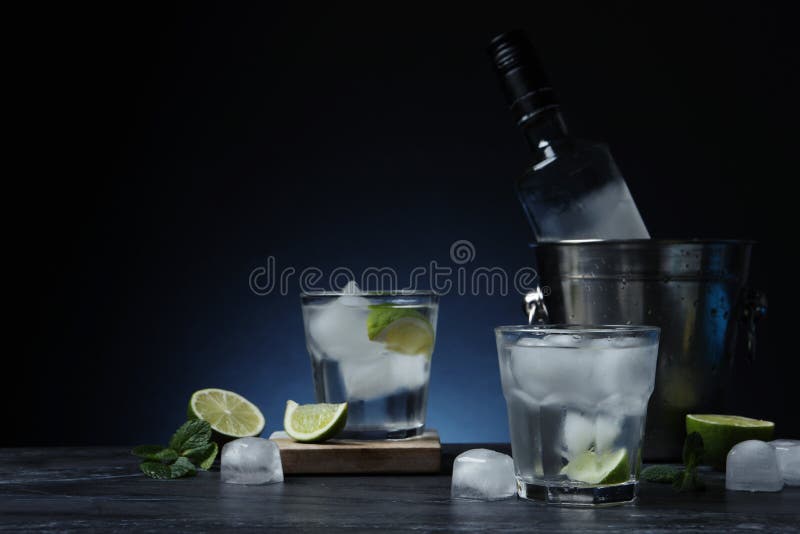 Bottle of Vodka, Glasses, Lime, Mint and Ice on Black Marble Table ...