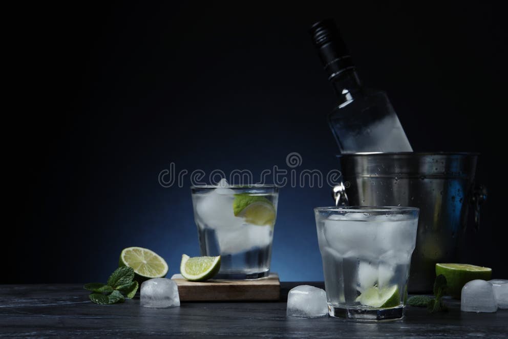 Bottle of Vodka, Glasses, Lime, Mint and Ice on Black Marble Table ...