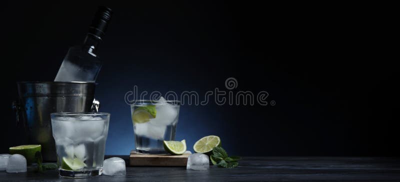 Bottle of Vodka, Glasses, Lime, Mint and Ice on Black Marble Table ...