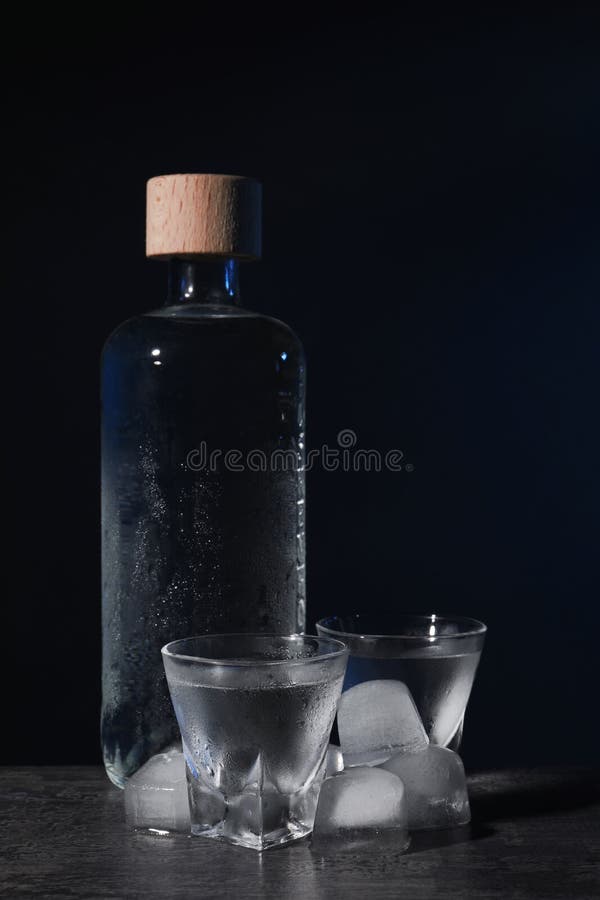 Bottle of Vodka and Shot Glasses with Ice on Black Table Against Dark Background Stock Image ...